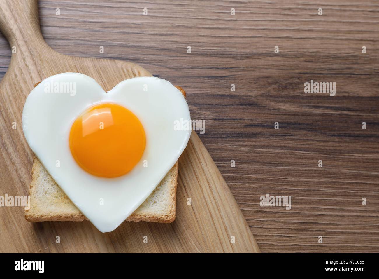 Heart shaped fried egg and toast on wooden table, top view. Space for text Stock Photo - Alamy