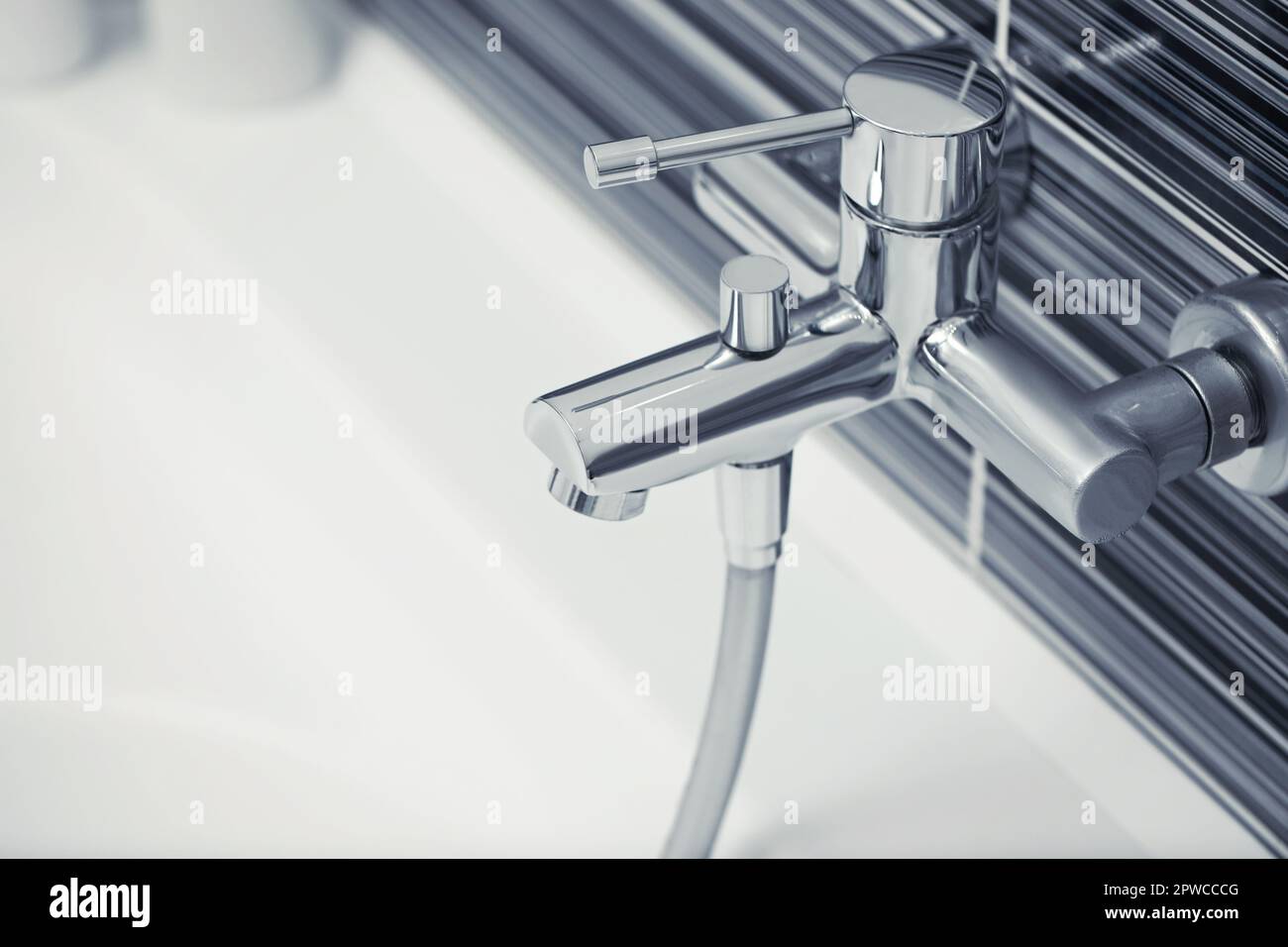 Shiny water tap installed on black and white wall above bathtub Stock ...