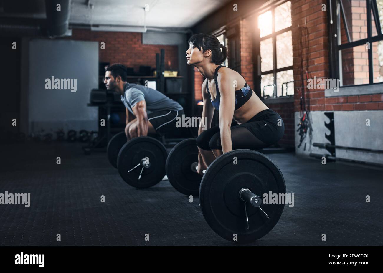 Going in for the lift. a young man and woman working out with weights ...