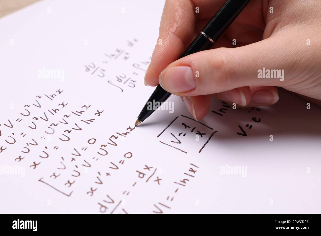 Student writing different mathematical formulas on paper, closeup Stock ...