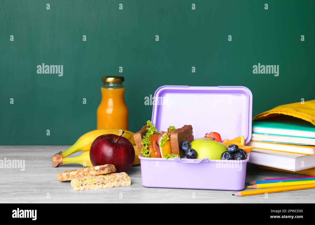 Lunch box with healthy food and different stationery on light wooden ...