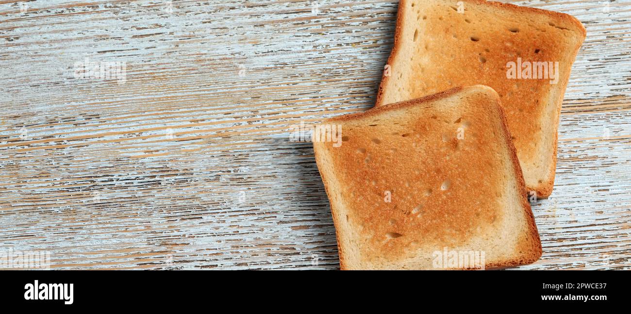 Slices of delicious toasted bread on wooden table, top view with space ...