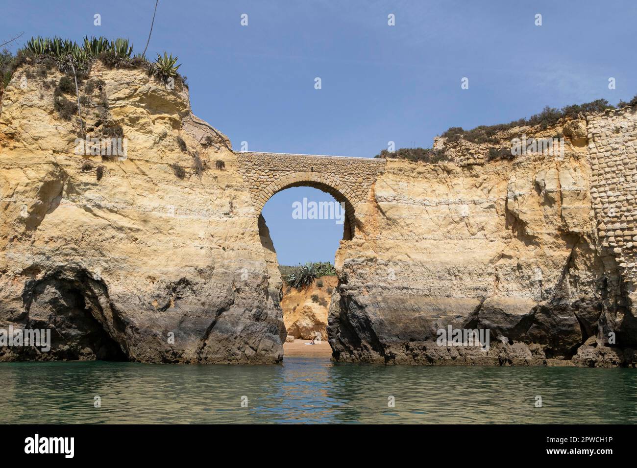 Historic Roman stone bridge at Praia da Batata beach in the rocky coast ...