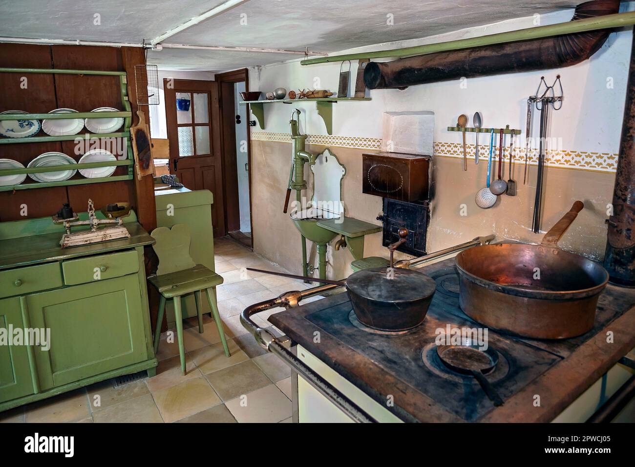 Kitchen with old wood or coal cooker and hand-operated swing pump ...