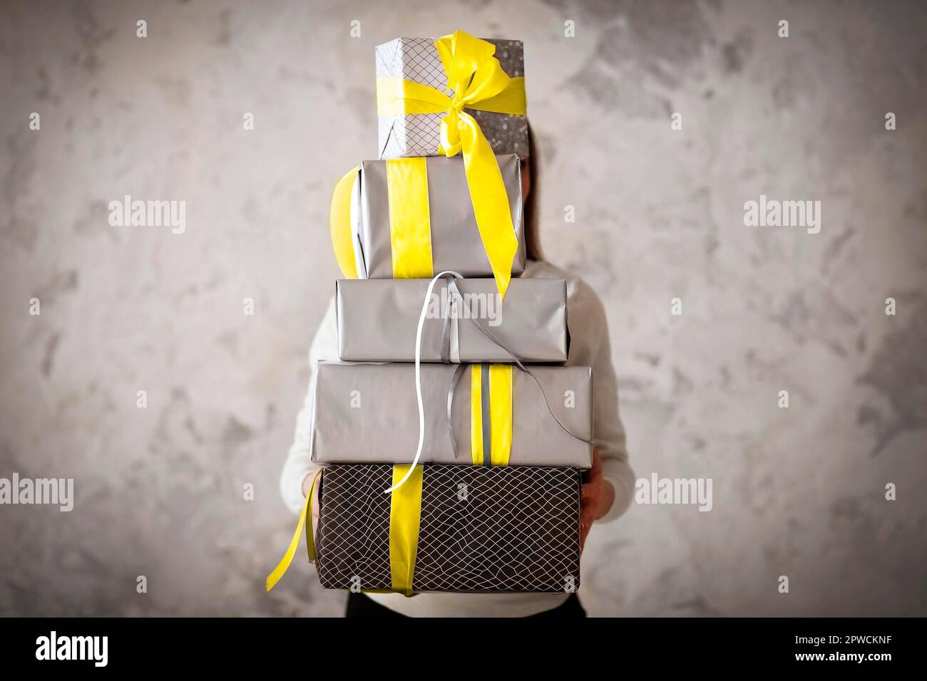Female holding big stack of presents wrapped in ultimate gray color ...