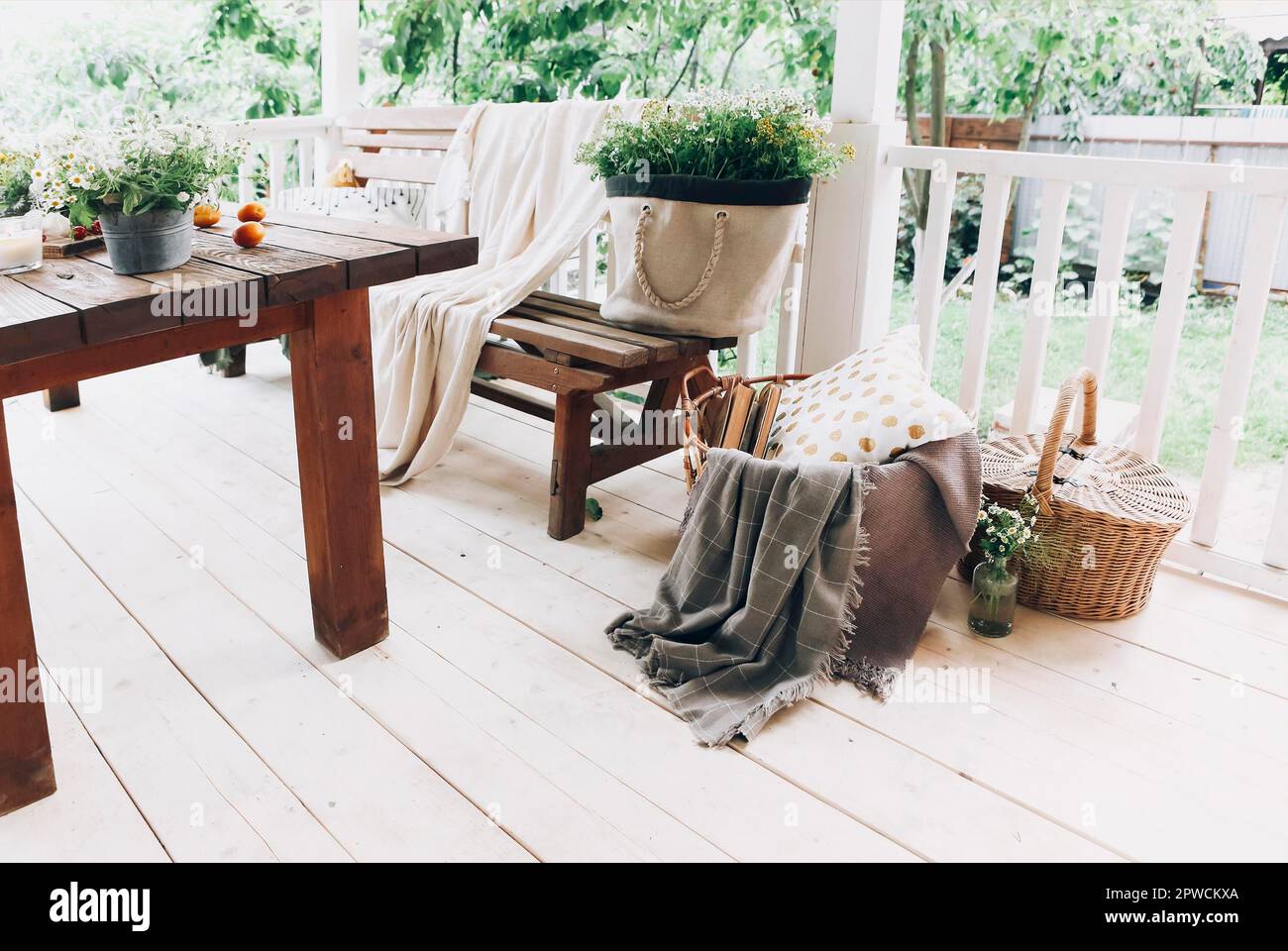 High angle of wooden terrace of house with bench and bunch of flowers ...