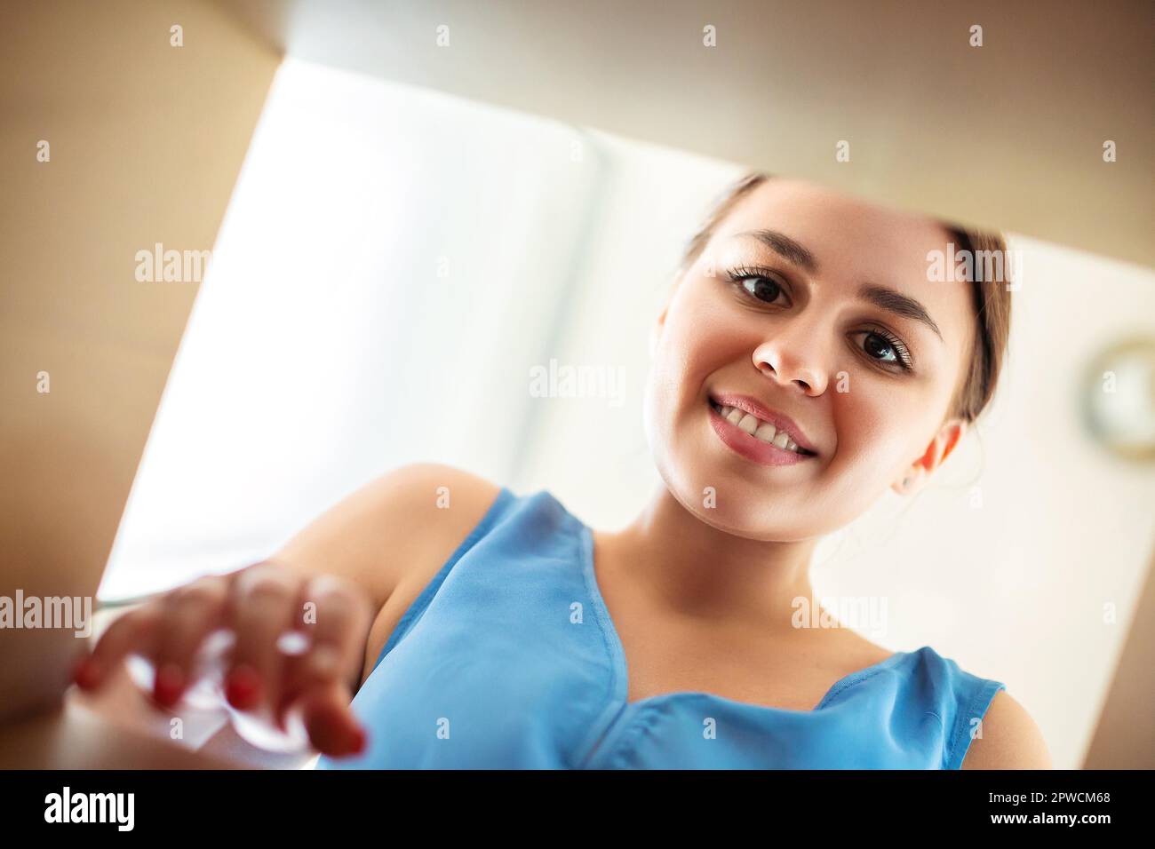 From below happy young female smiling and looking inside carton box ...