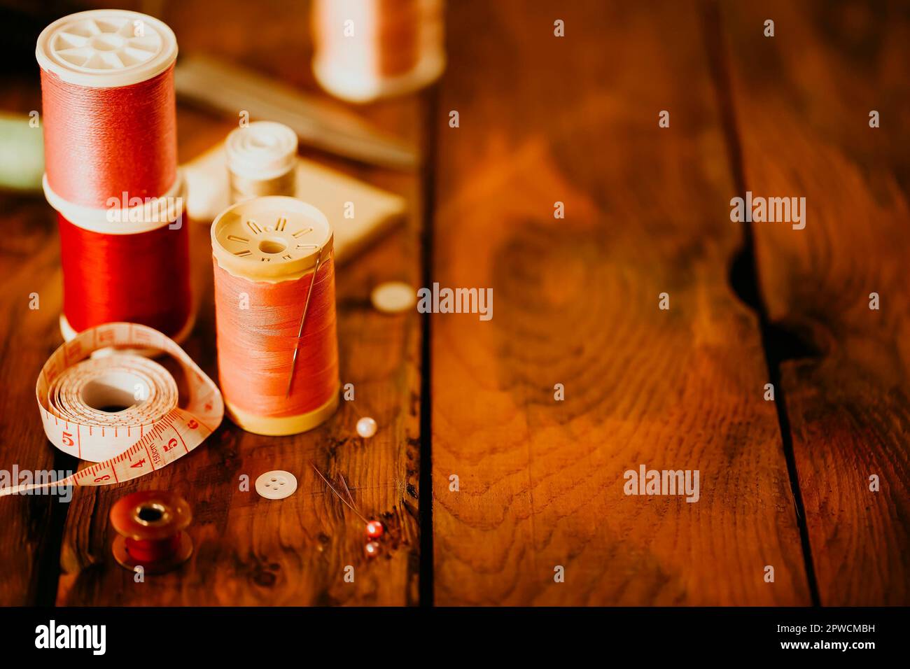 Tape measure and needles placed near threads on lumber table in tailor ...