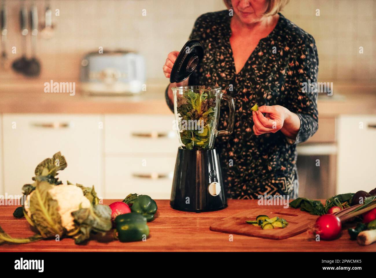 Crop Middle Aged Female Putting Ripe Vegetables Into Blender While