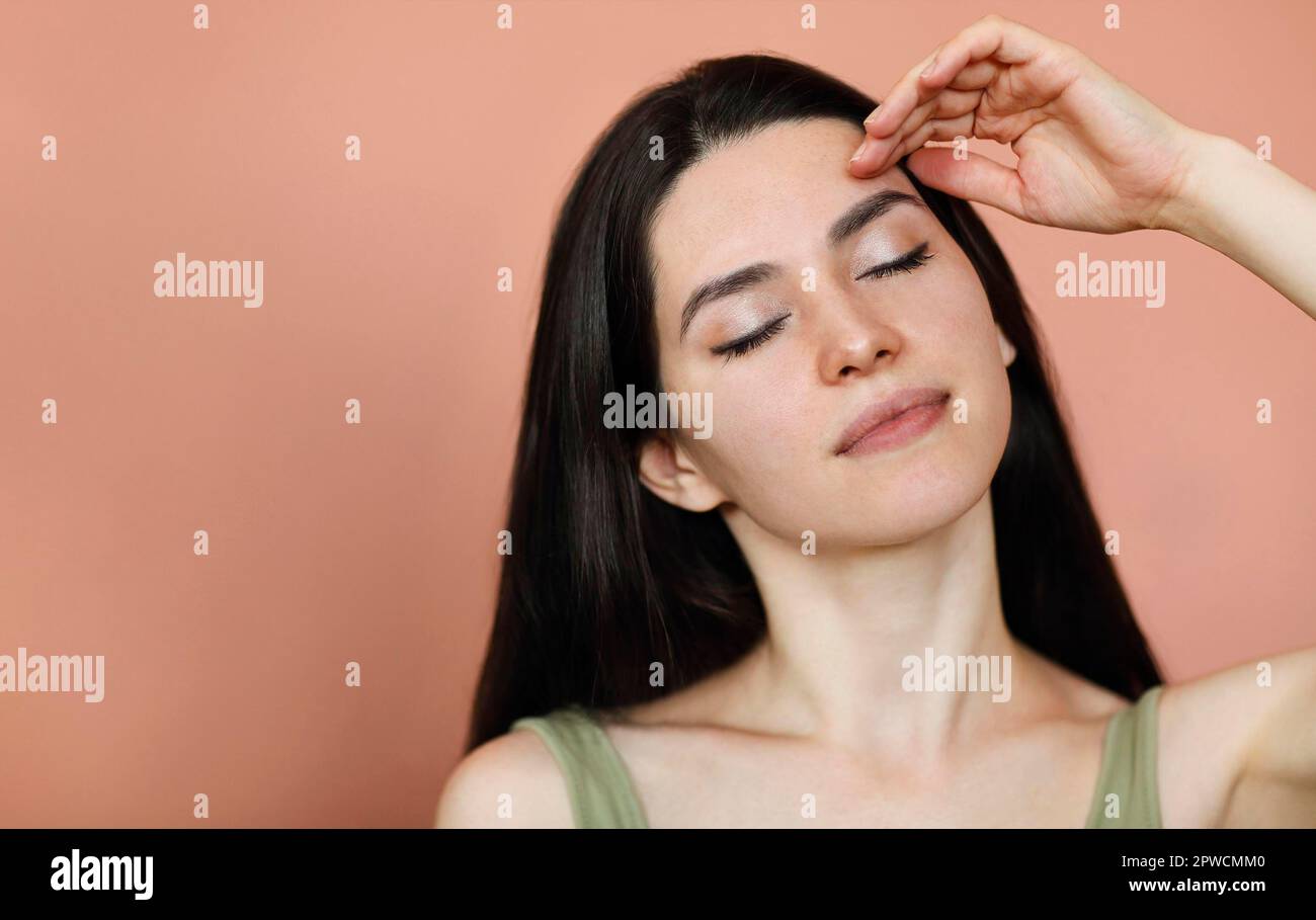 Young gentle female in casual wear and with long hair standing on pink ...