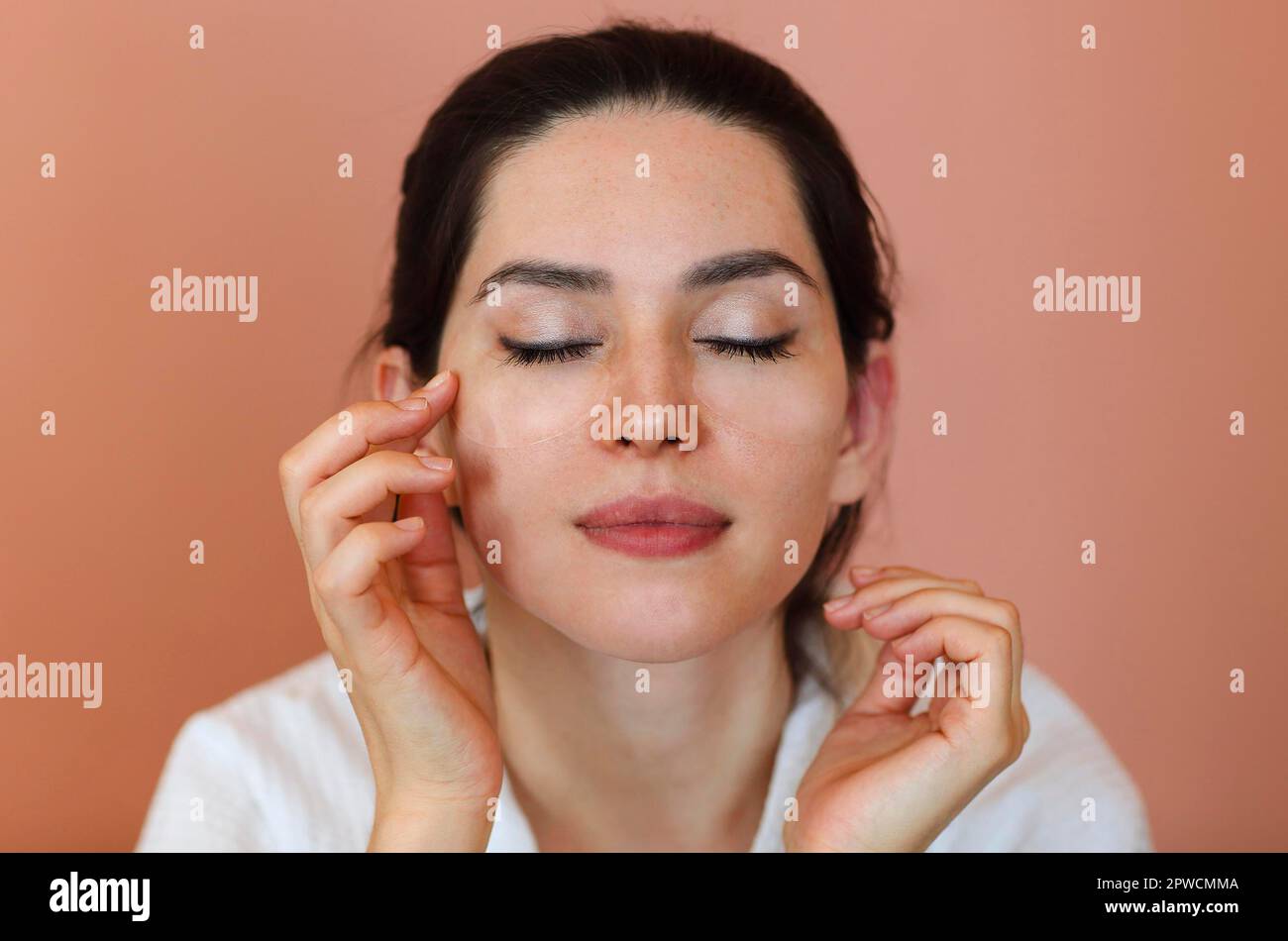 Positive young brunette female with eye patches touching her face and ...