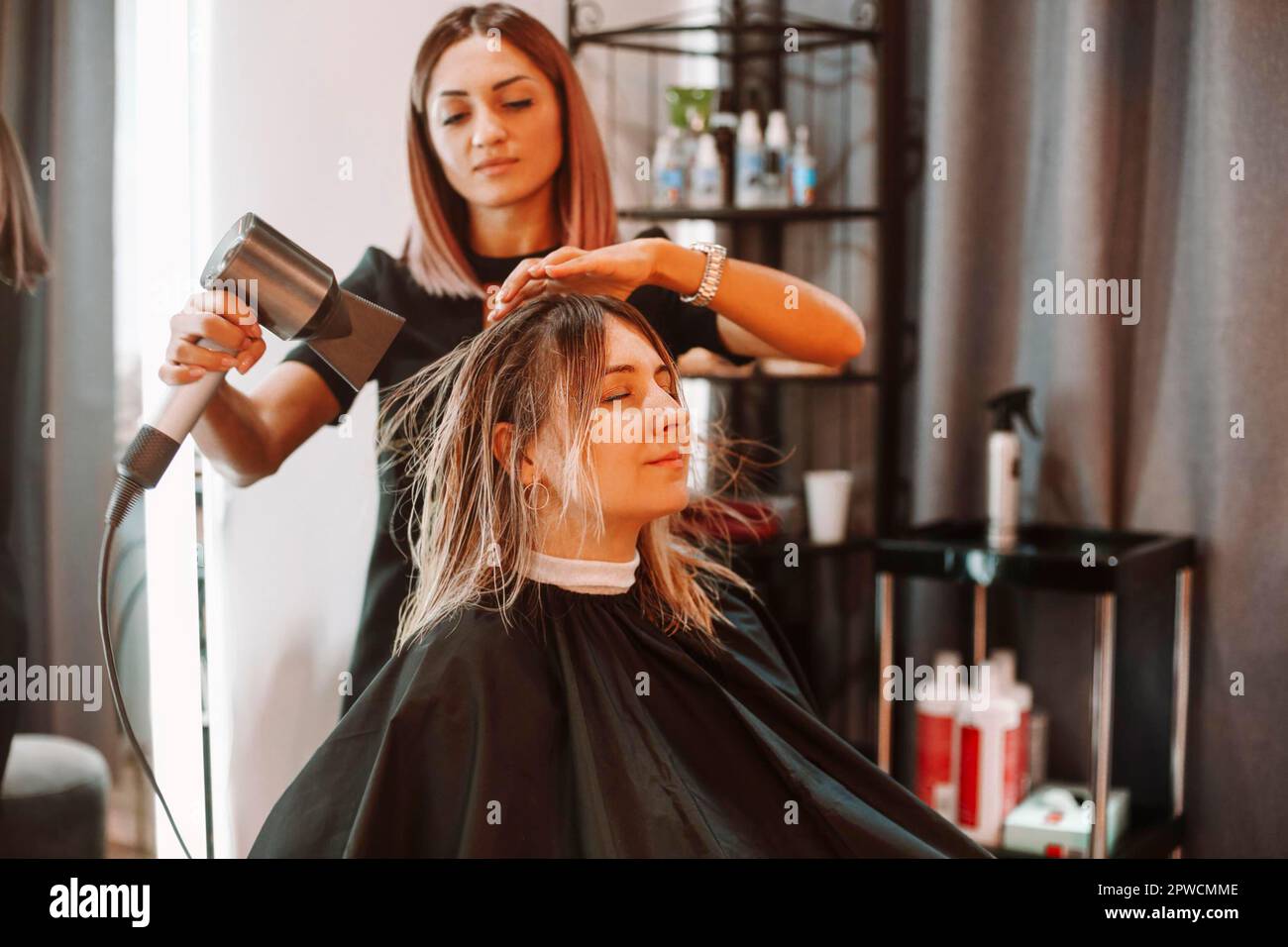 Happy woman with stylist making hairdo at salon. Competent female ...