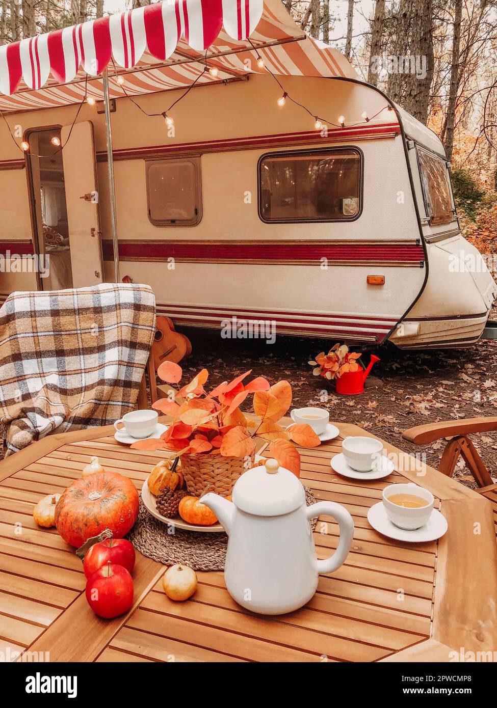 Wooden chairs and table with tea set placed outside cozy retro caravan ...