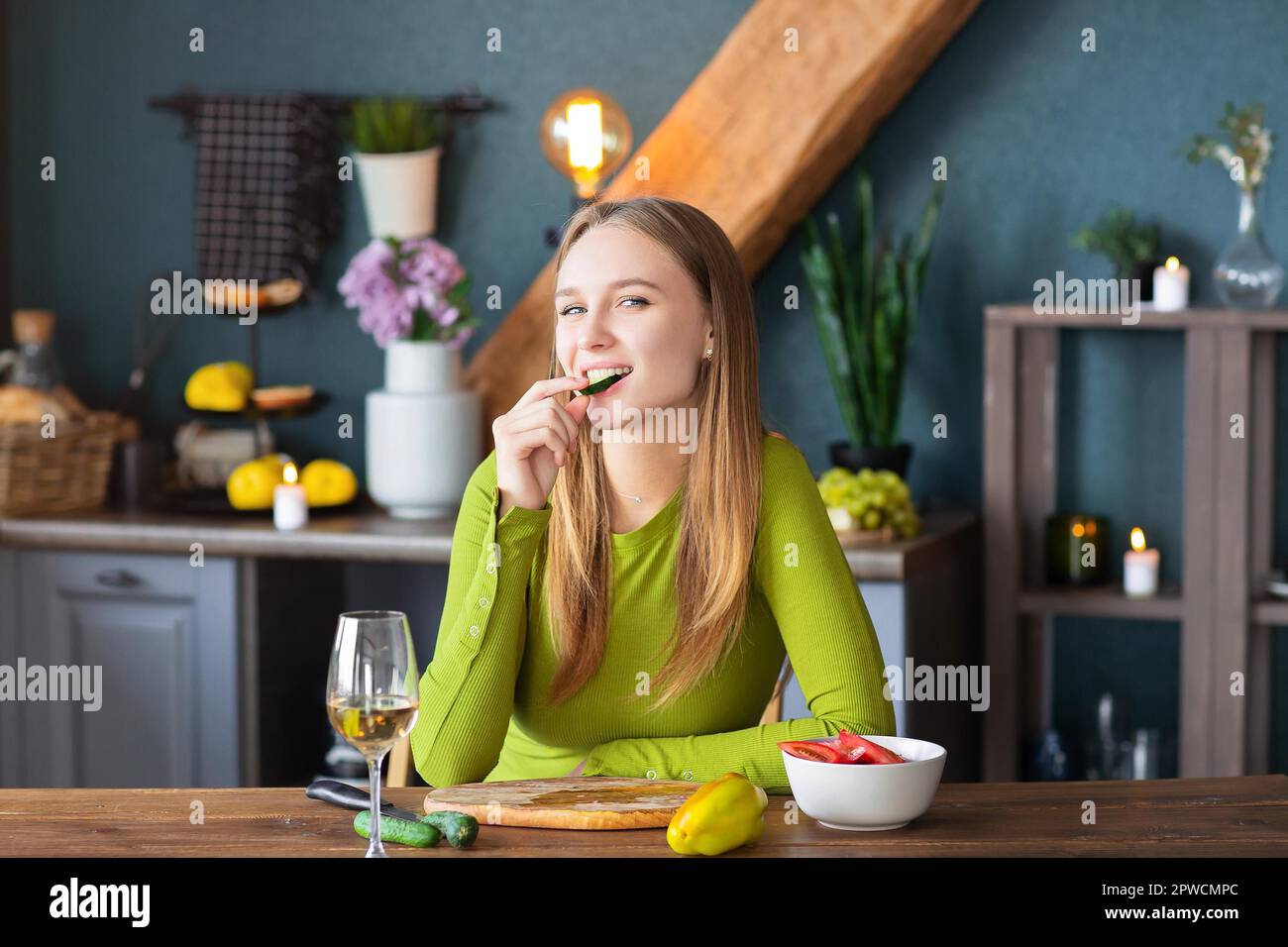Happy blond woman making salad kitchen vegetables cooking and drinking ...