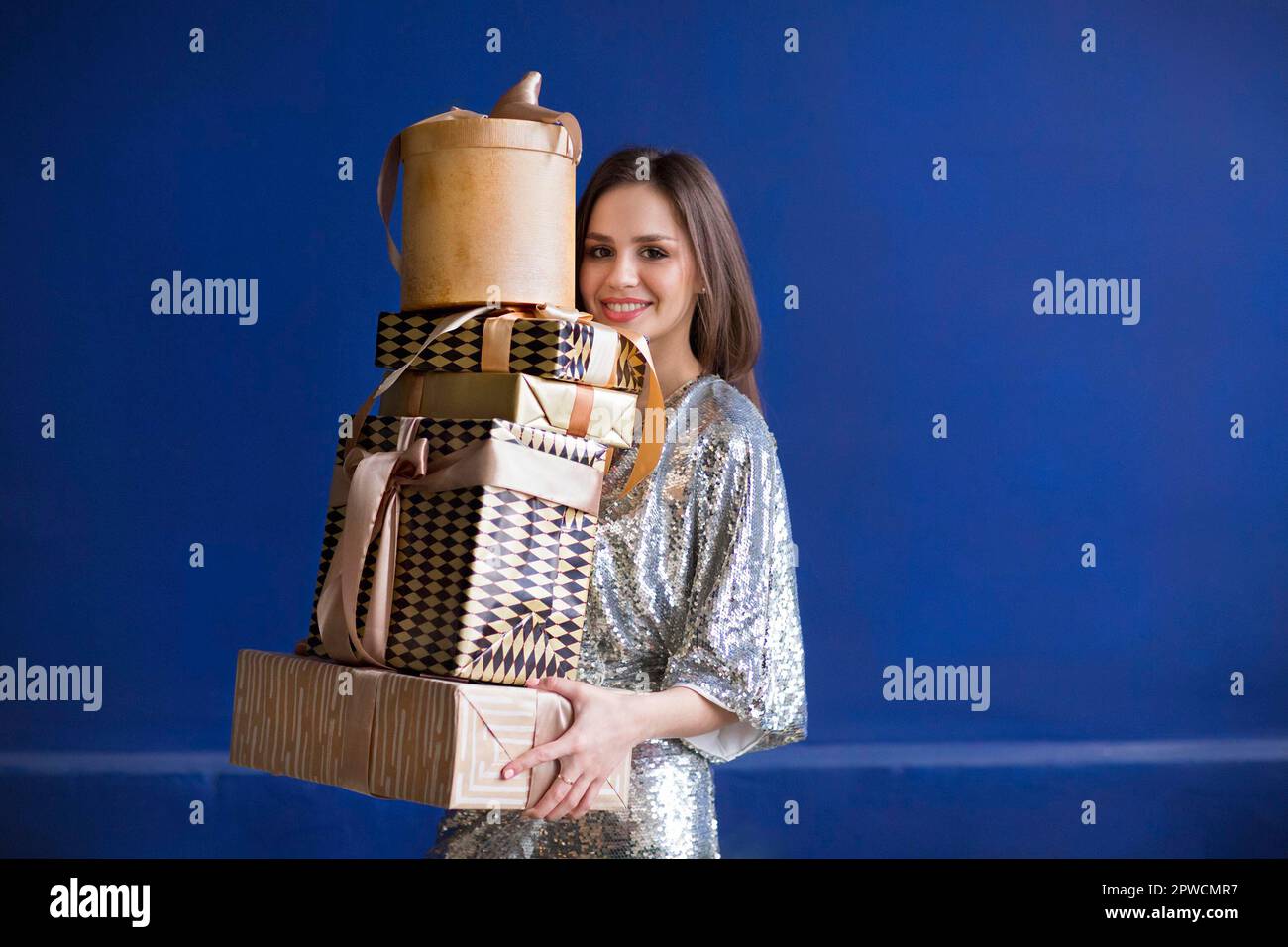 Female holding big stack of presents wrapped in golden paper with white ...