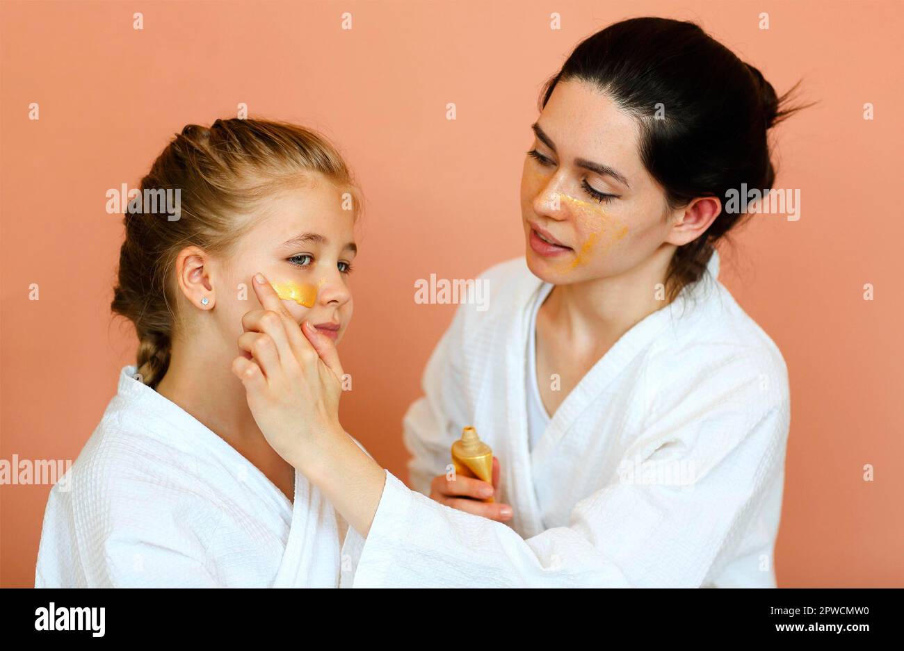 Family spa day. Young beautiful mother and little daughter in bathrobes ...