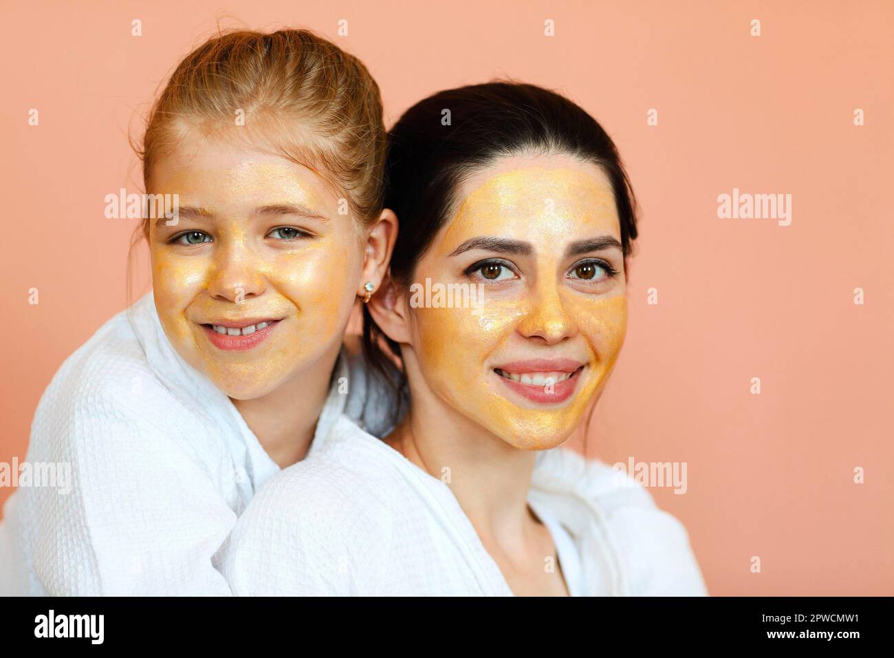 Family spa day. Young beautiful mother and little daughter in bathrobes ...