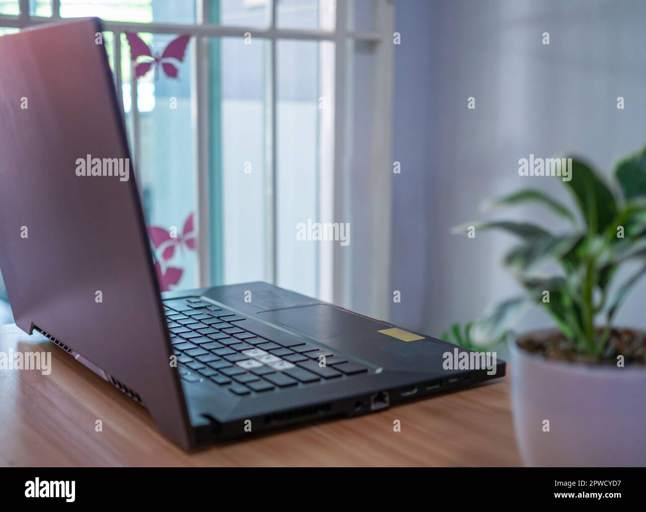 Rear view of laptop computer on wooden table with window blurred ...