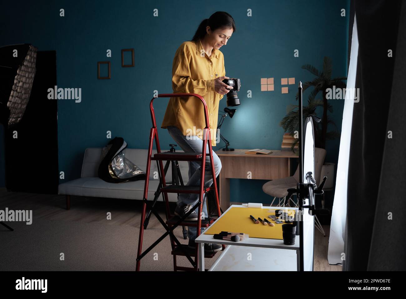 Female photographer setting up camera in home studio. Modern blogger ...