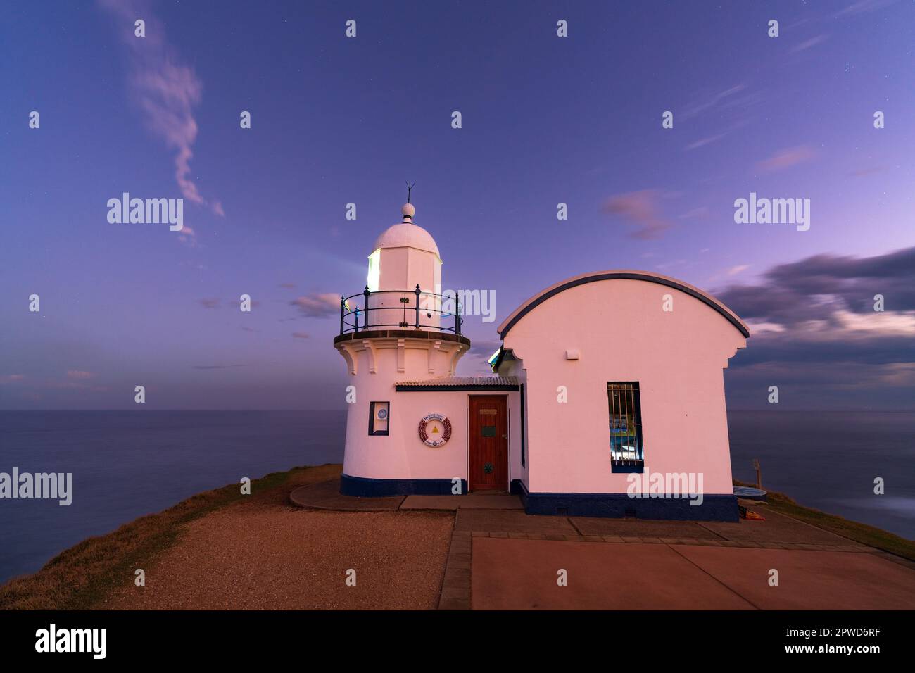 A short lighthouse and keepers quarters on a hill top at twilight on ...