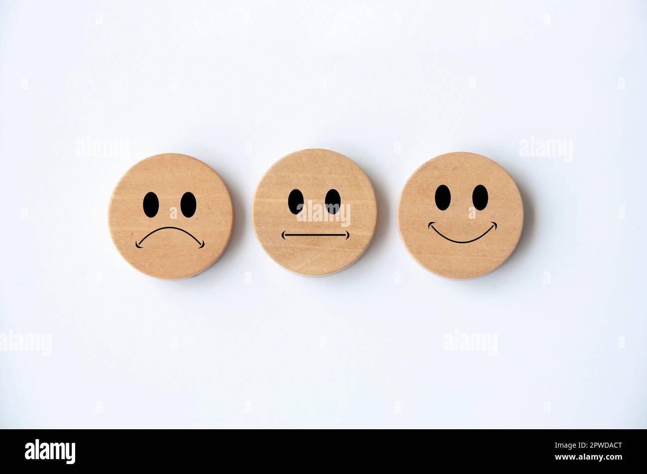 Happy, sad and neutral emoticon faces on wooden circle with white ...