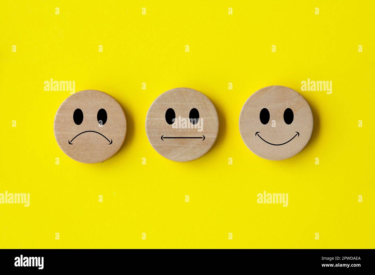 Happy, sad and neutral emoticon faces on wooden circle with yellow ...