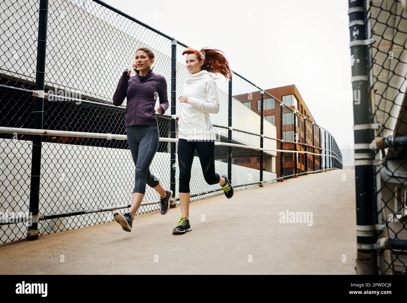 Matching one another stride for stride. Full length shot of two attractive young women running ...