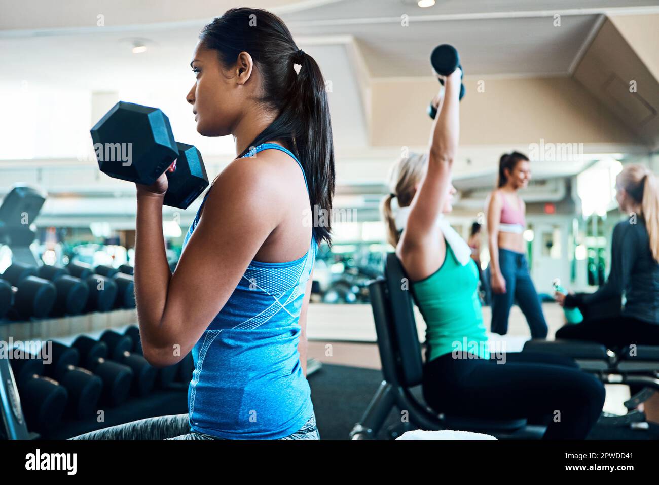 Lift your game. attractive young women working out with dumbbells at ...