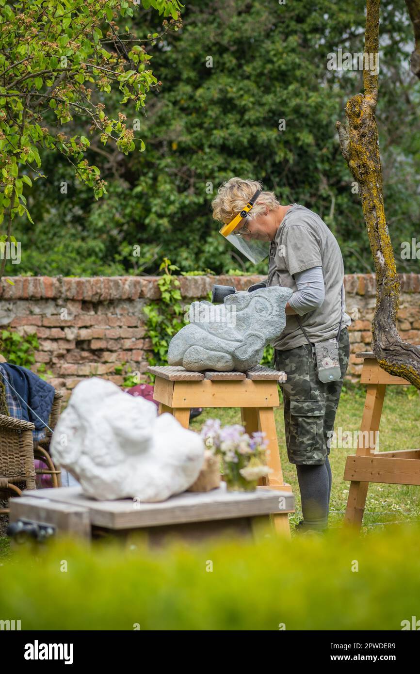 Woman carving a stone during an outdoor sculpture lesson or class in ...
