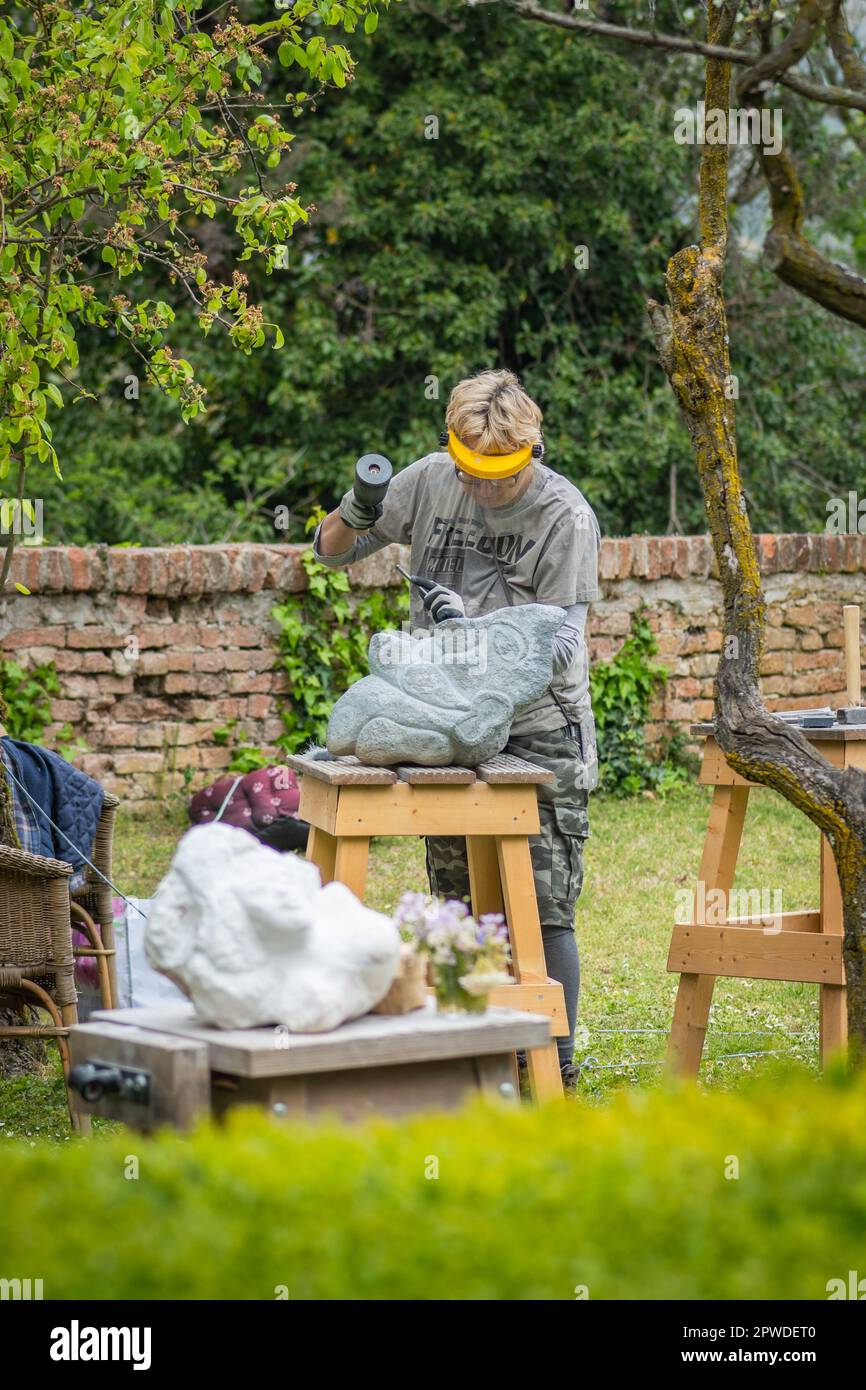 Woman carving a stone during an outdoor sculpture lesson or class in ...