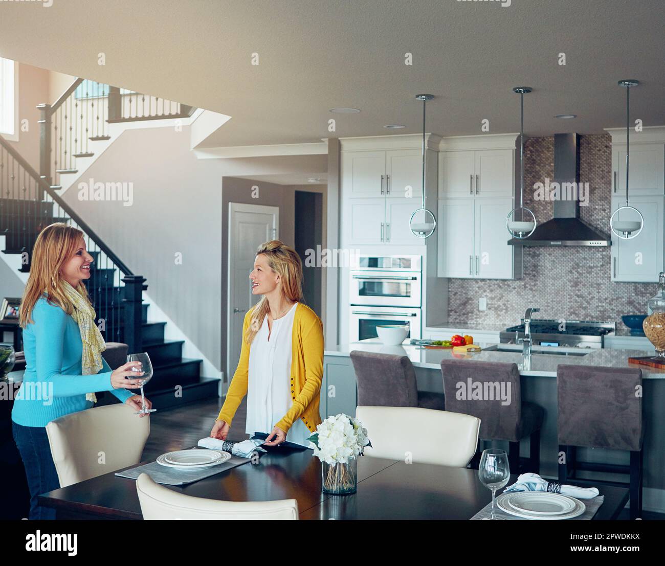 Shes staying for dinner. two women setting up the dining room table ...