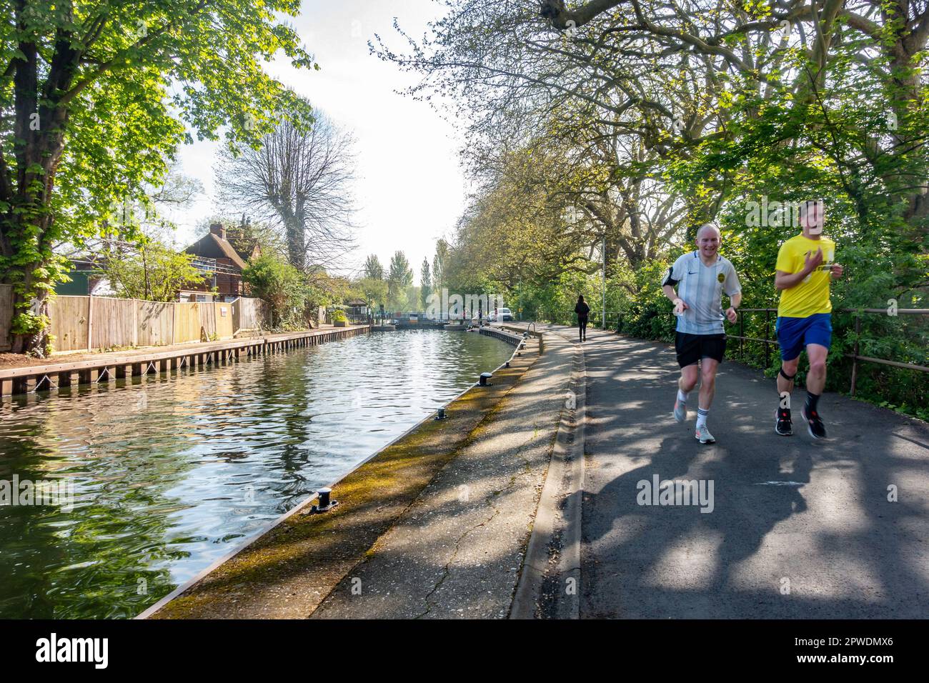 A couple of men jog along a path running alongside The River Thames at ...