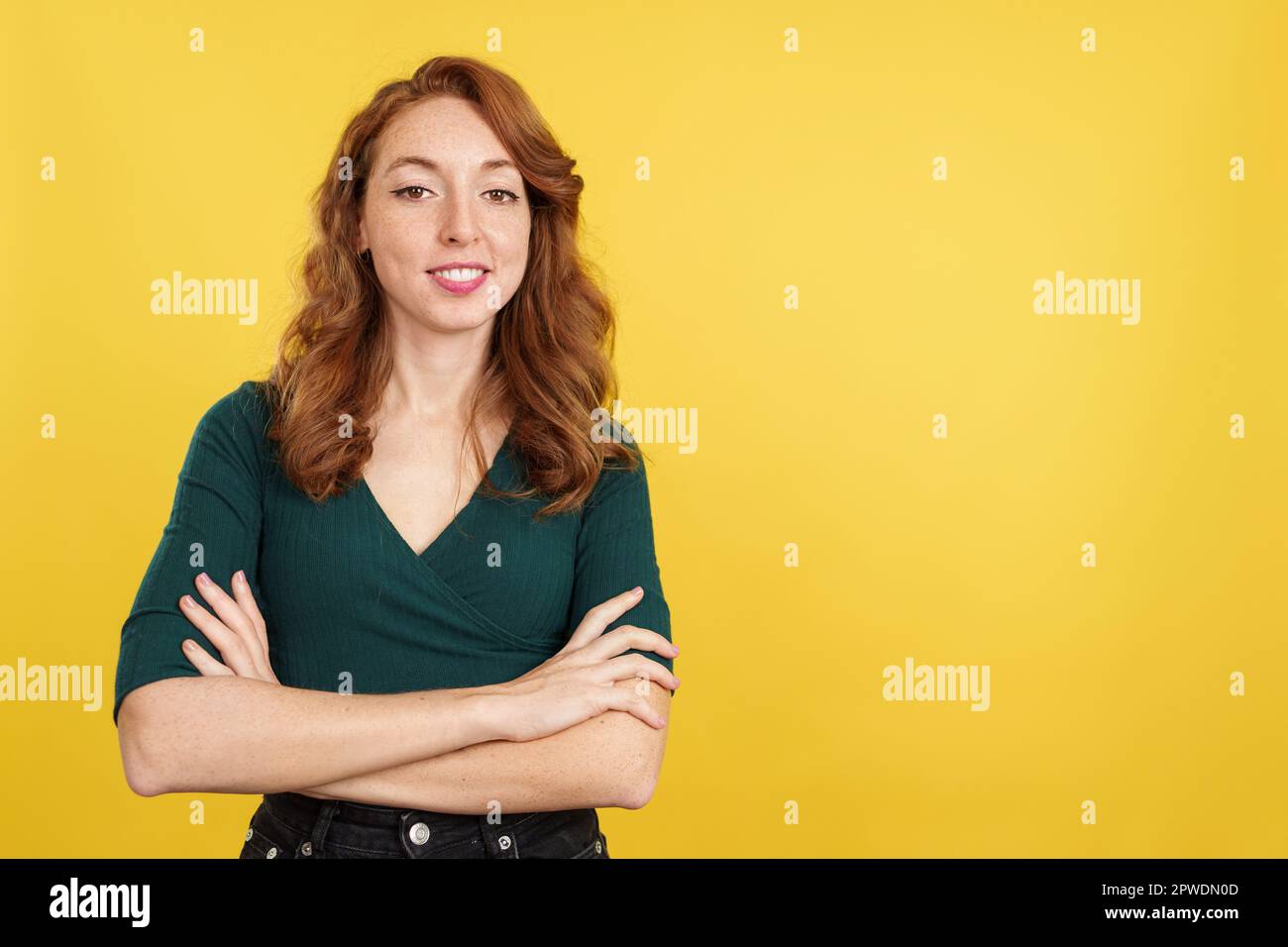 Redheaded woman standing with arms crossed smiling at the camera Stock ...