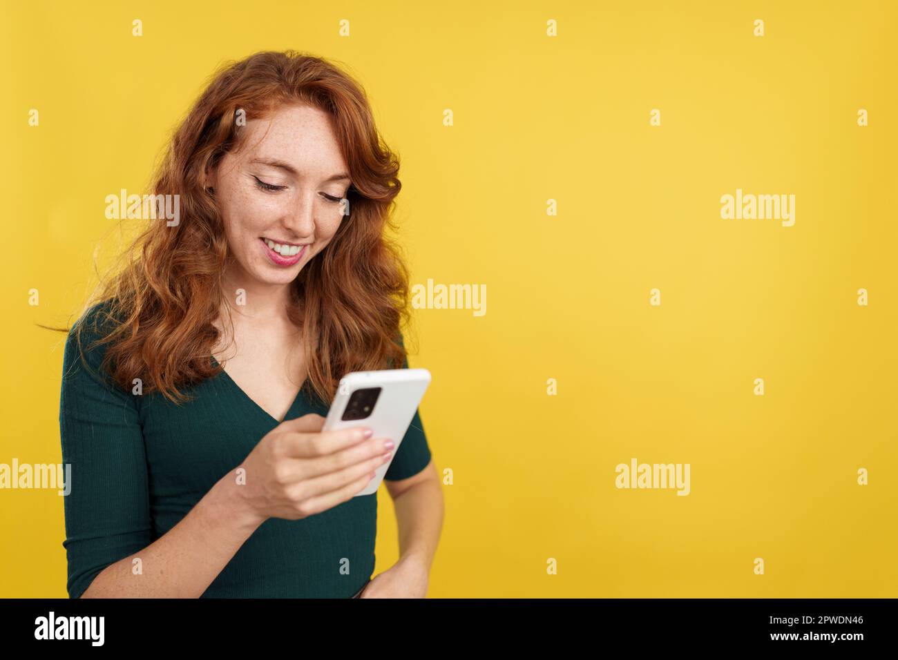 Happy redheaded woman smiling while using the mobile Stock Photo - Alamy