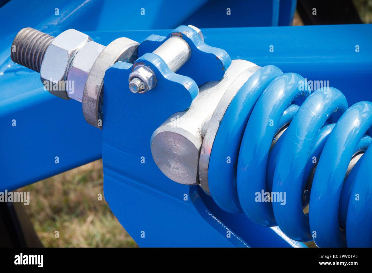 Hard blue spring made of steel. Part of big industrial or agricultural ...