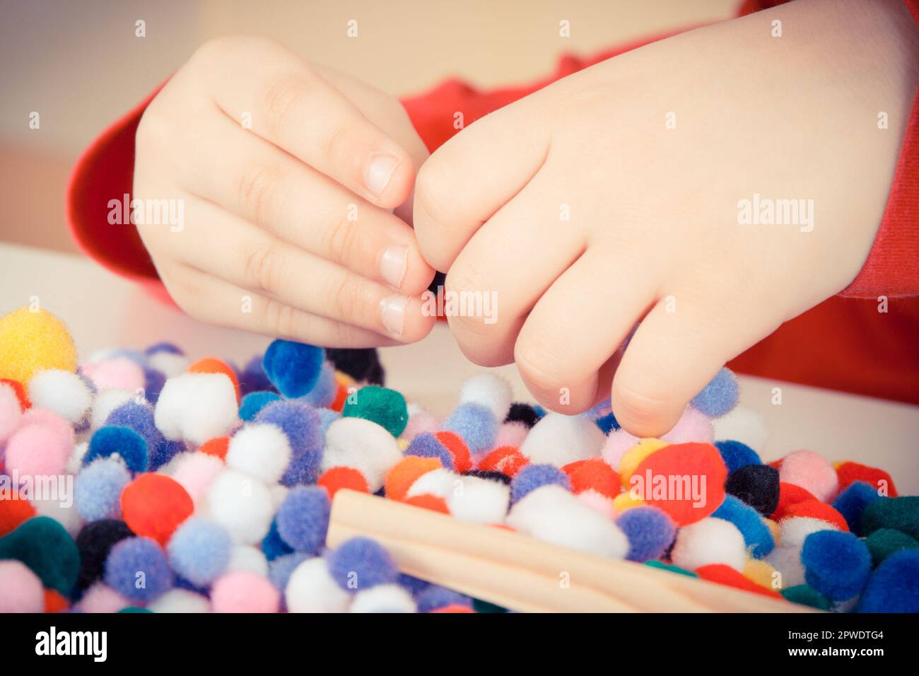 Preschooler playing with small fluffy colorful pompoms. Development of ...