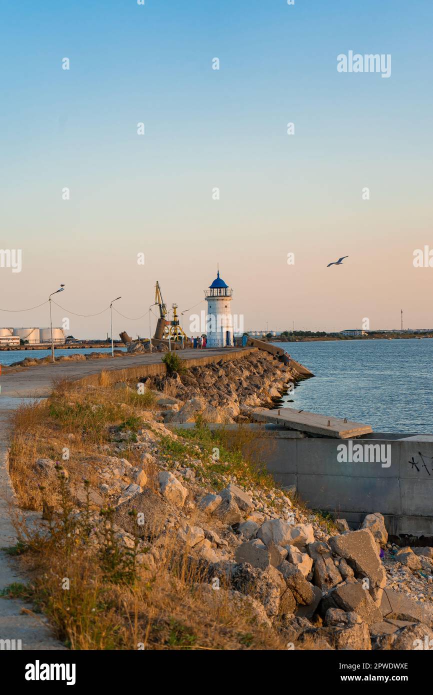 The Genoese lighthouse with a blue roof, on the rocky pier in a port on ...