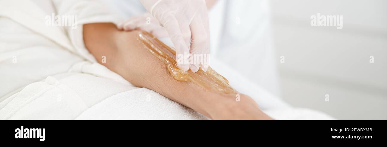 Professional is doing hair sugaring depilation on female hand in ...
