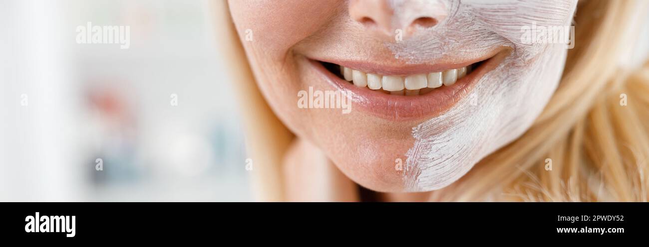 Close up shot of unrecognizable woman with white cream mask on a half ...
