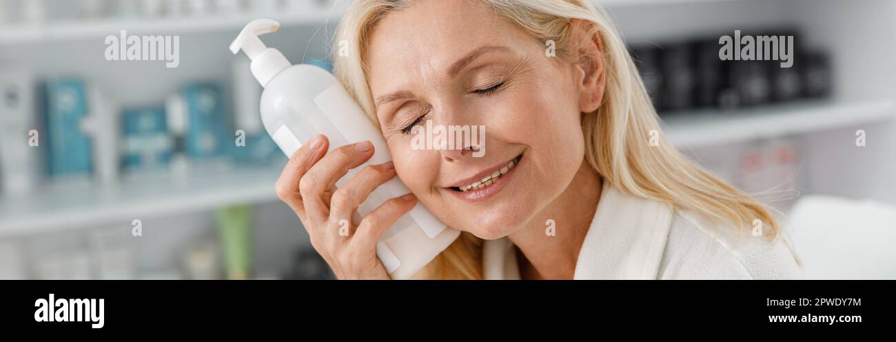 Senior smiling female patient sitting in wellness center holding bottle ...