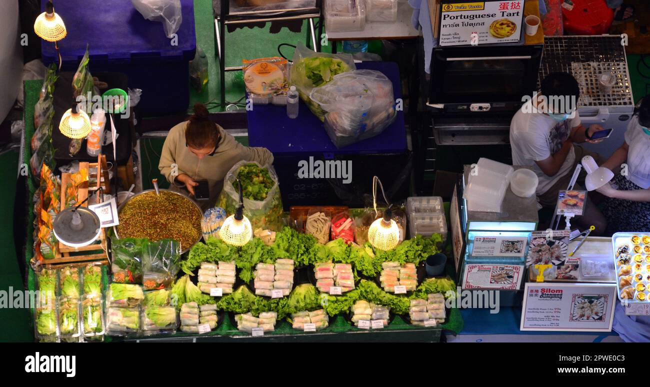 Overhead view of a food stall in Bangkok, Thailand. The staff look at ...