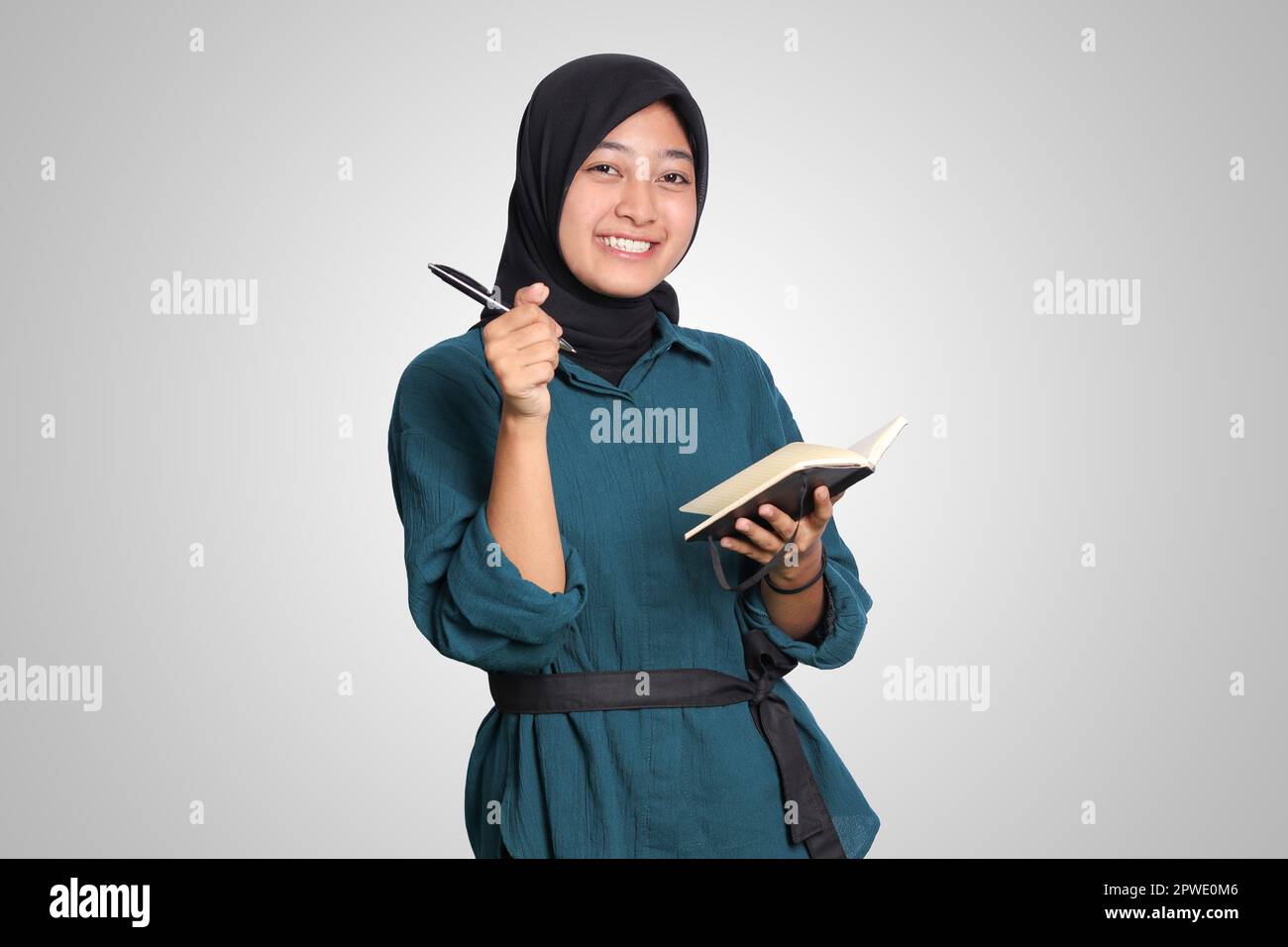 Portrait of excited Asian muslim woman with hijab writing on pocket ...