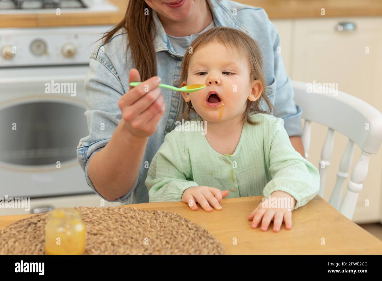 Happy family at home. Mother feeding her baby girl from spoon in ...