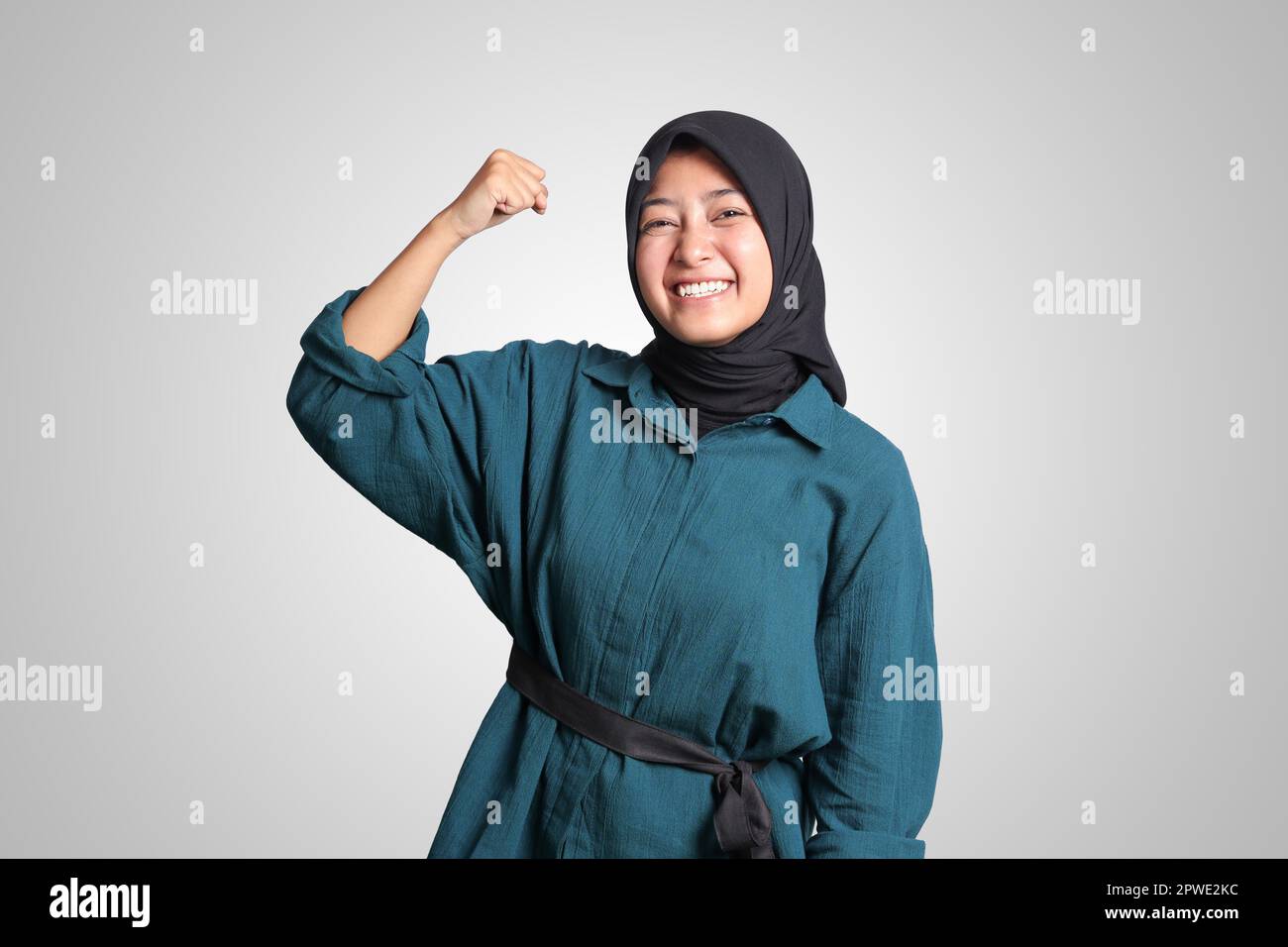 Portrait of excited Asian muslim woman with hijab raising her fist ...