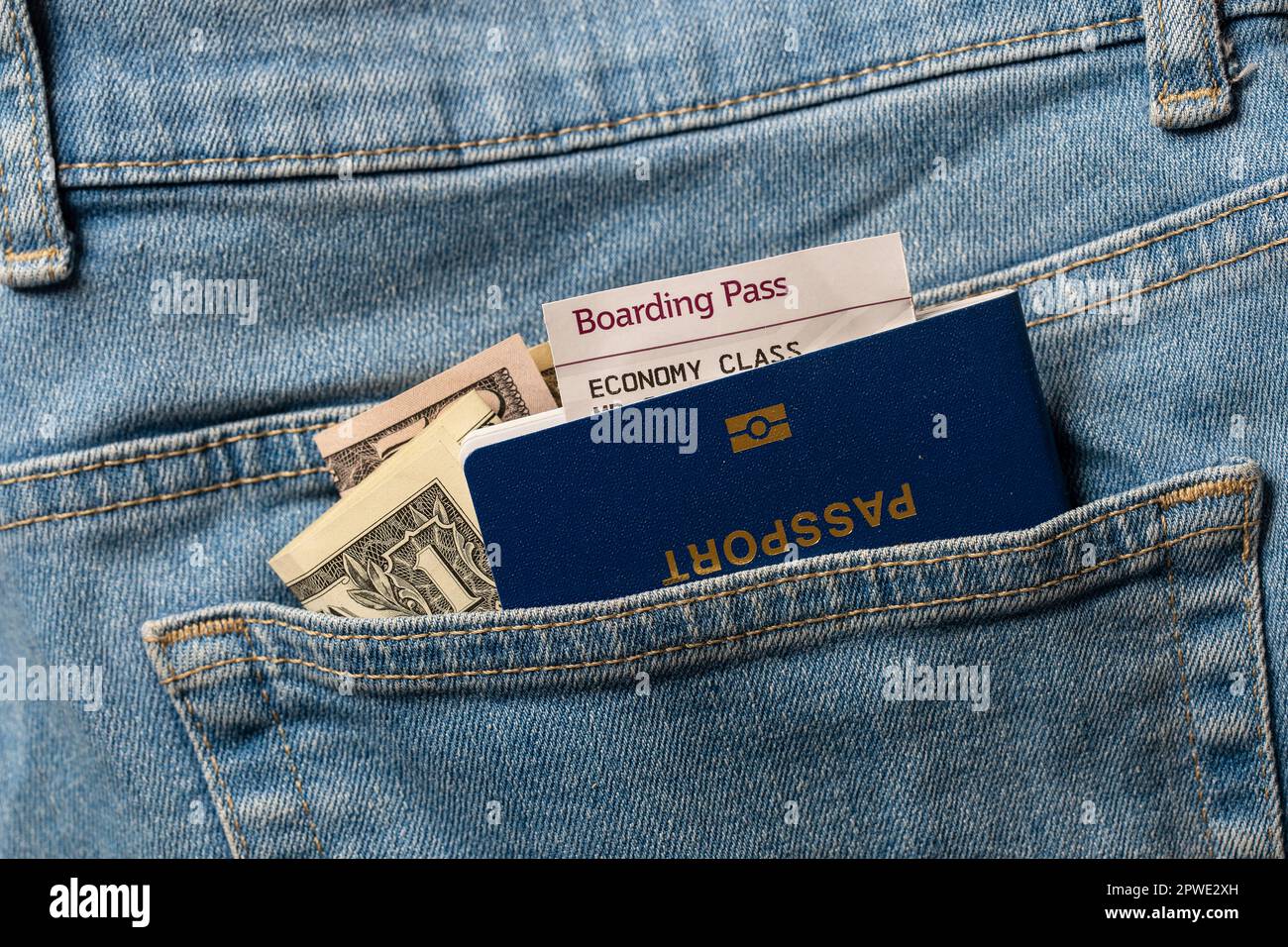 Dollars, blue passport and boarding pass in your pocket jeans, close up ...
