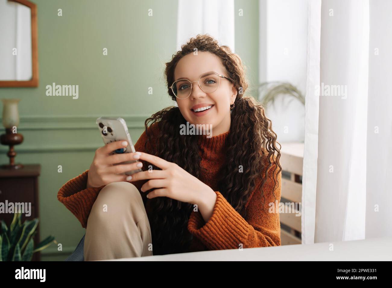 Happy woman using cell phone technology at home, smiling while checking ...