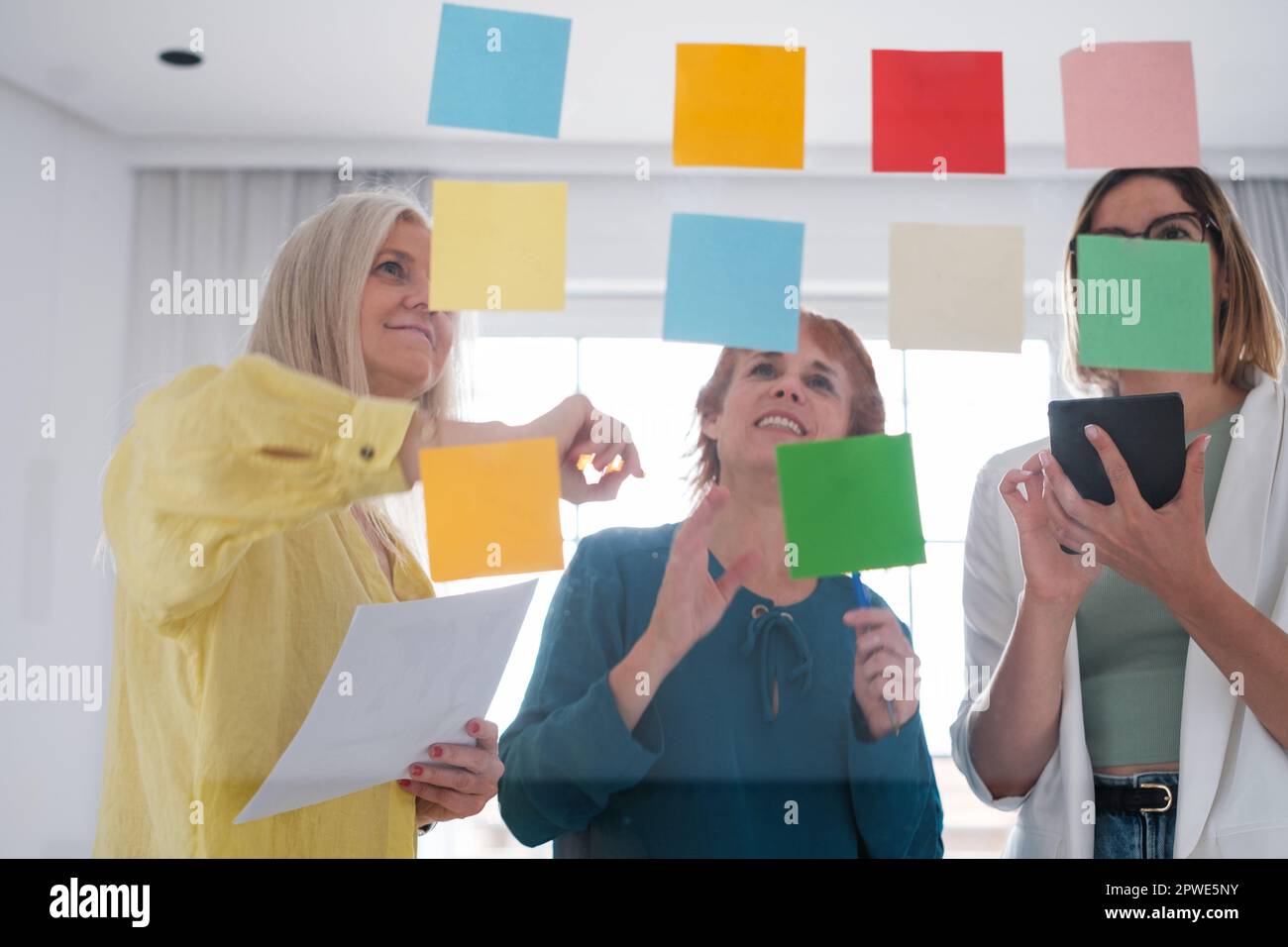 Women writing down ideas and innovations on post-it notes to make ...