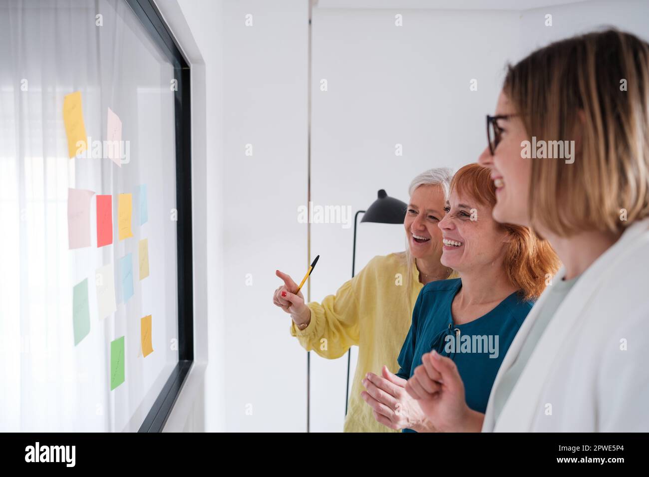 Start up of women pointing the brainstorm on a transparent whiteboard ...