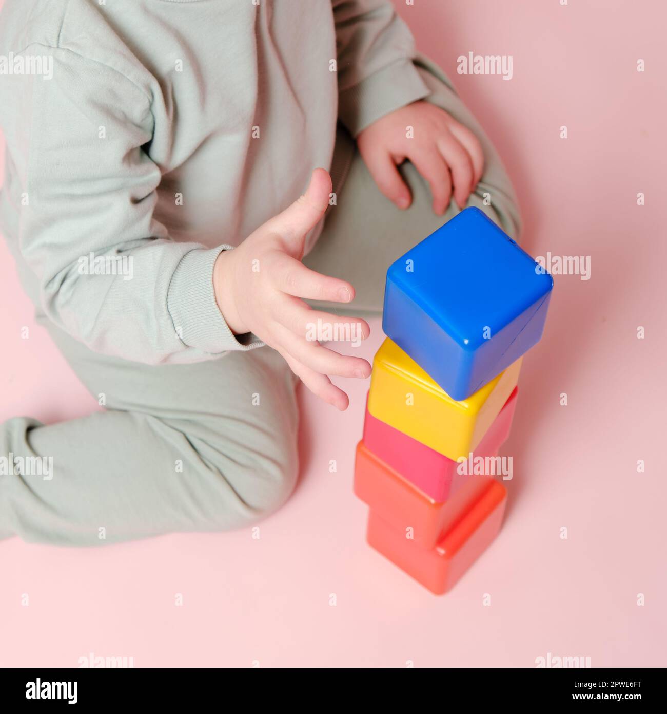 Happy toddler baby plays with cubes on studio pink background. Child ...