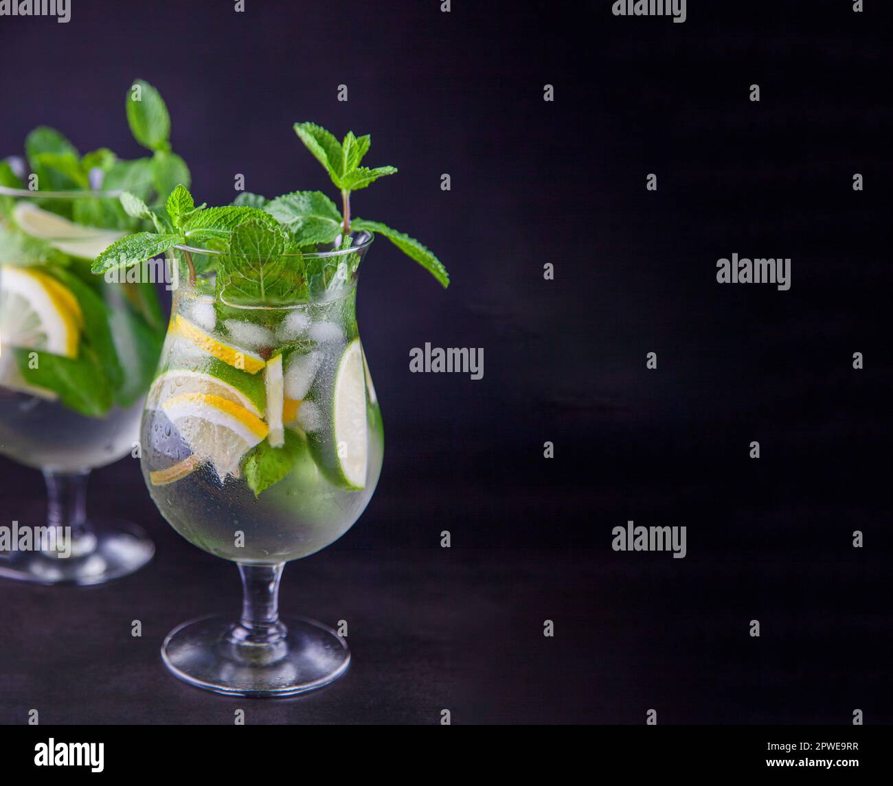 Summer mint lime refreshing cocktail mojito with ice in glass on black ...